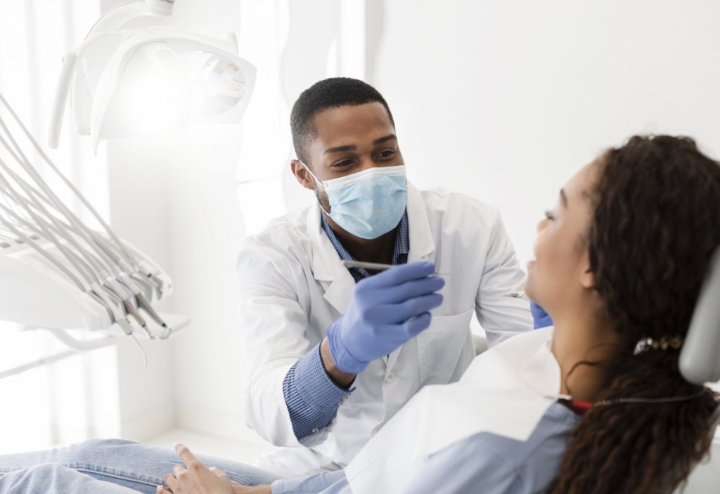 African american dentist making treatment in modern clinic - Delta ...